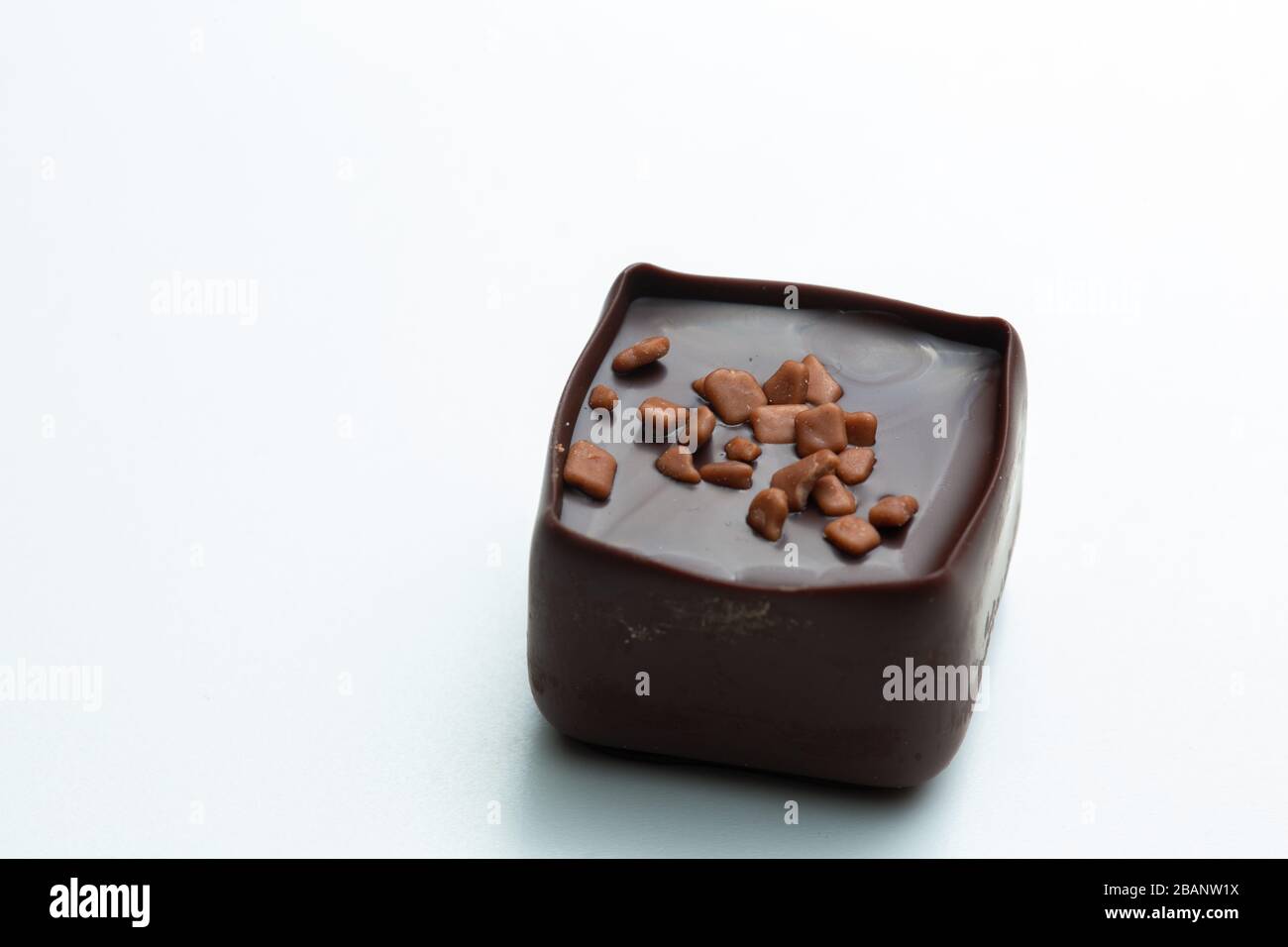 Closeup shot of a square prism shape chocolate laid on a white surface ...