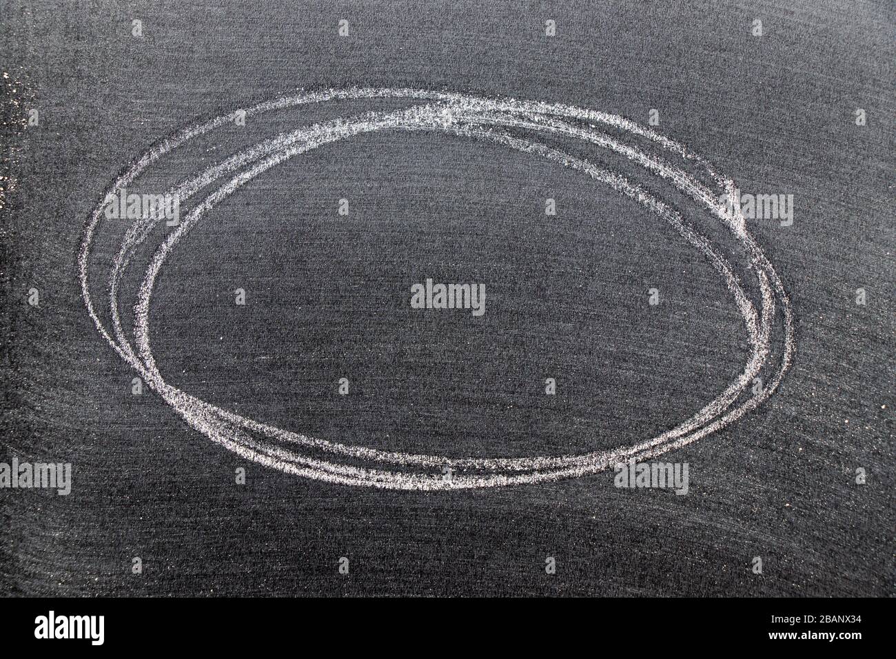 White color chalk hand drawing in circle or oval shape on black board ...