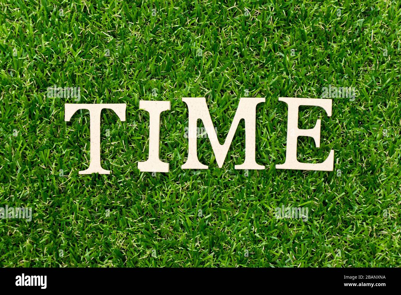 Wood letter in word time on green grass background Stock Photo - Alamy
