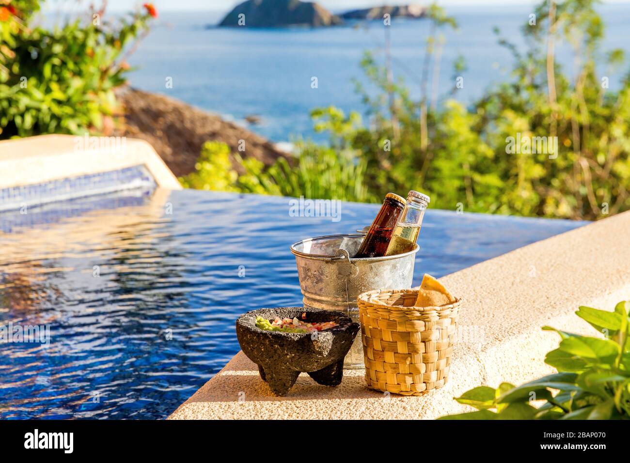 Beer in a bucket with chips and guacamole sitting on the edge of a pool ...