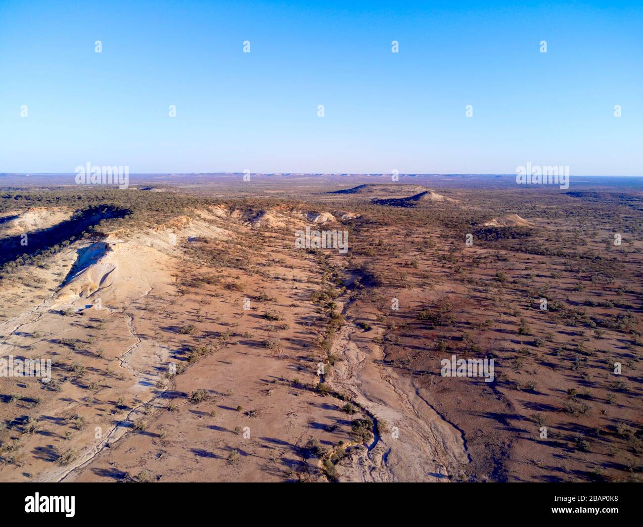 Aerial of dry creek as it passes through arid landscape near ...