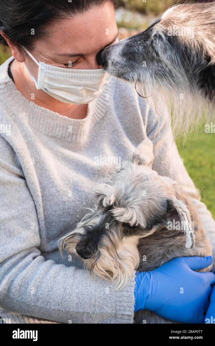 A woman protected with a procedure mask and blue medical gloves hugs ...