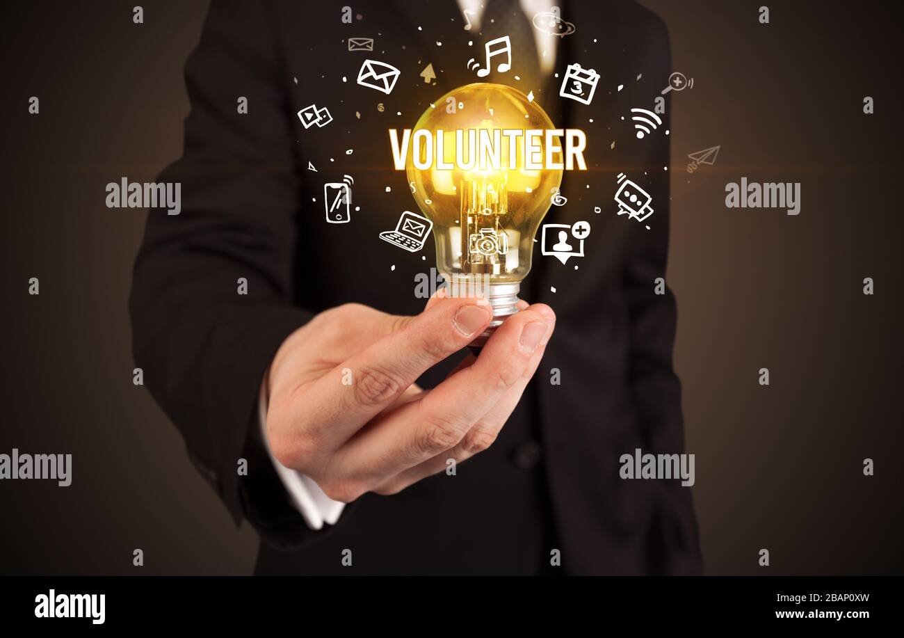 Businessman holding light bulb with VOLUNTEER inscription, social media ...