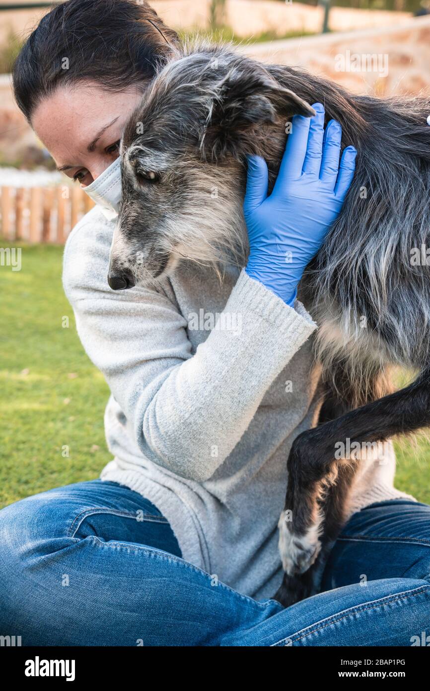 A woman protected with a procedure mask and blue medical gloves hugs ...