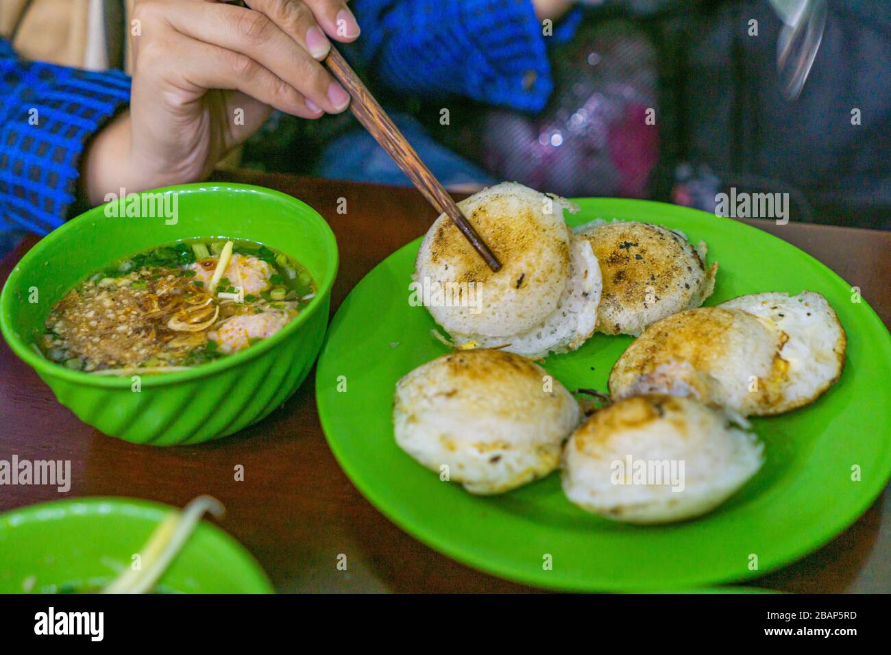 Woman hand using chopsticks while eating Vietnamese cuisine- Banh Can ...