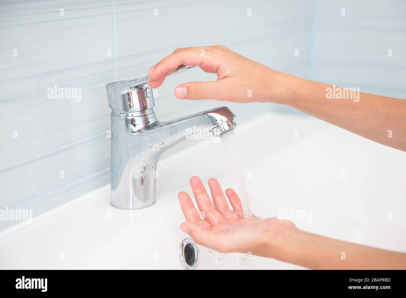 thin child small hands opening faucet with flowing water in bathroom ...