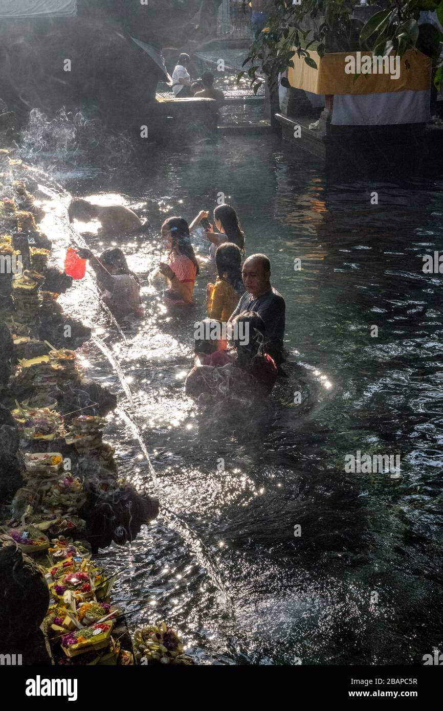 Balinese pilgrims bathing in early beautiful morning light, steam and ...