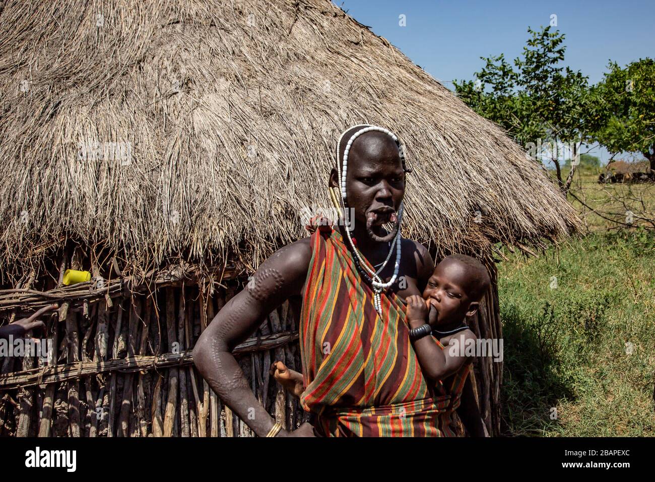 Woman of the Mursi tribe with clay lip disc as body holding a baby ...
