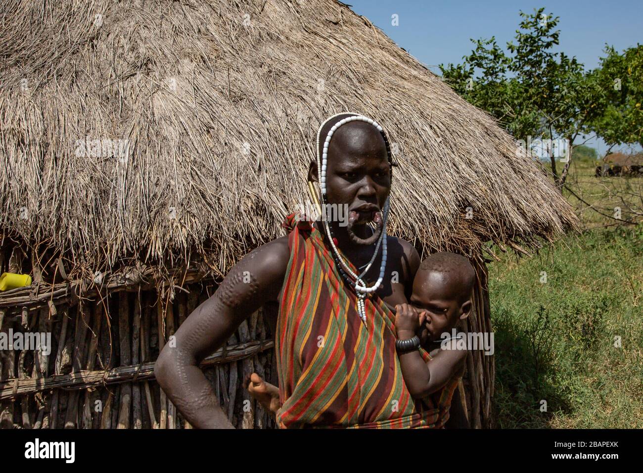 Woman of the Mursi tribe with clay lip disc as body holding a baby ...