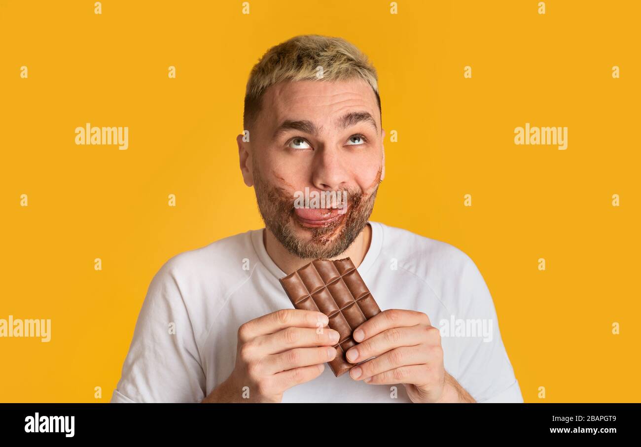 Funny guy eats chocolate and rolls his eyes Stock Photo - Alamy