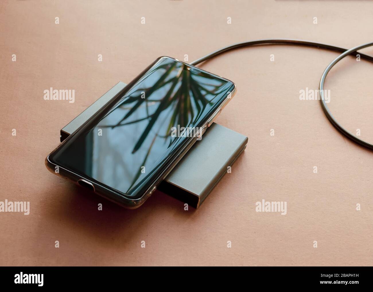 The phone is charging from a rectangular induction charger. Wireless ...