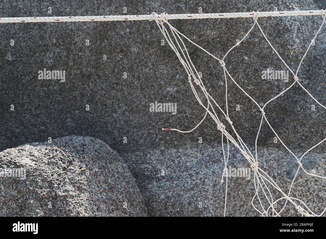 Old and torn white fishing net placed on the stones background with ...