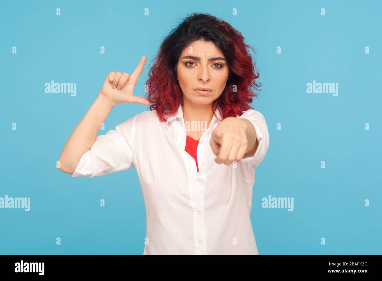 You are loser! Portrait of angry woman with fancy red hair showing L ...