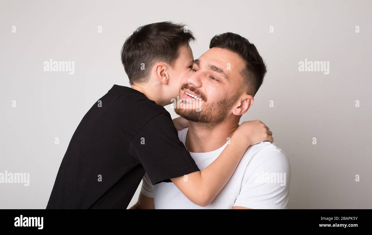Cheerful boy hugging with his father, gray studio background Stock ...