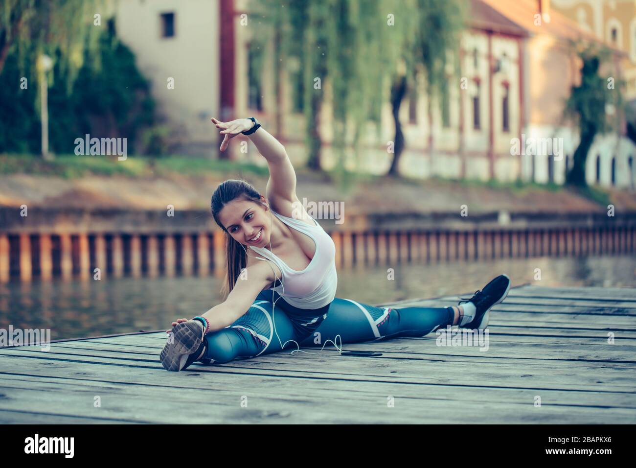 Young beautiful woman doing stretching exercises by the river Stock Photo - Alamy