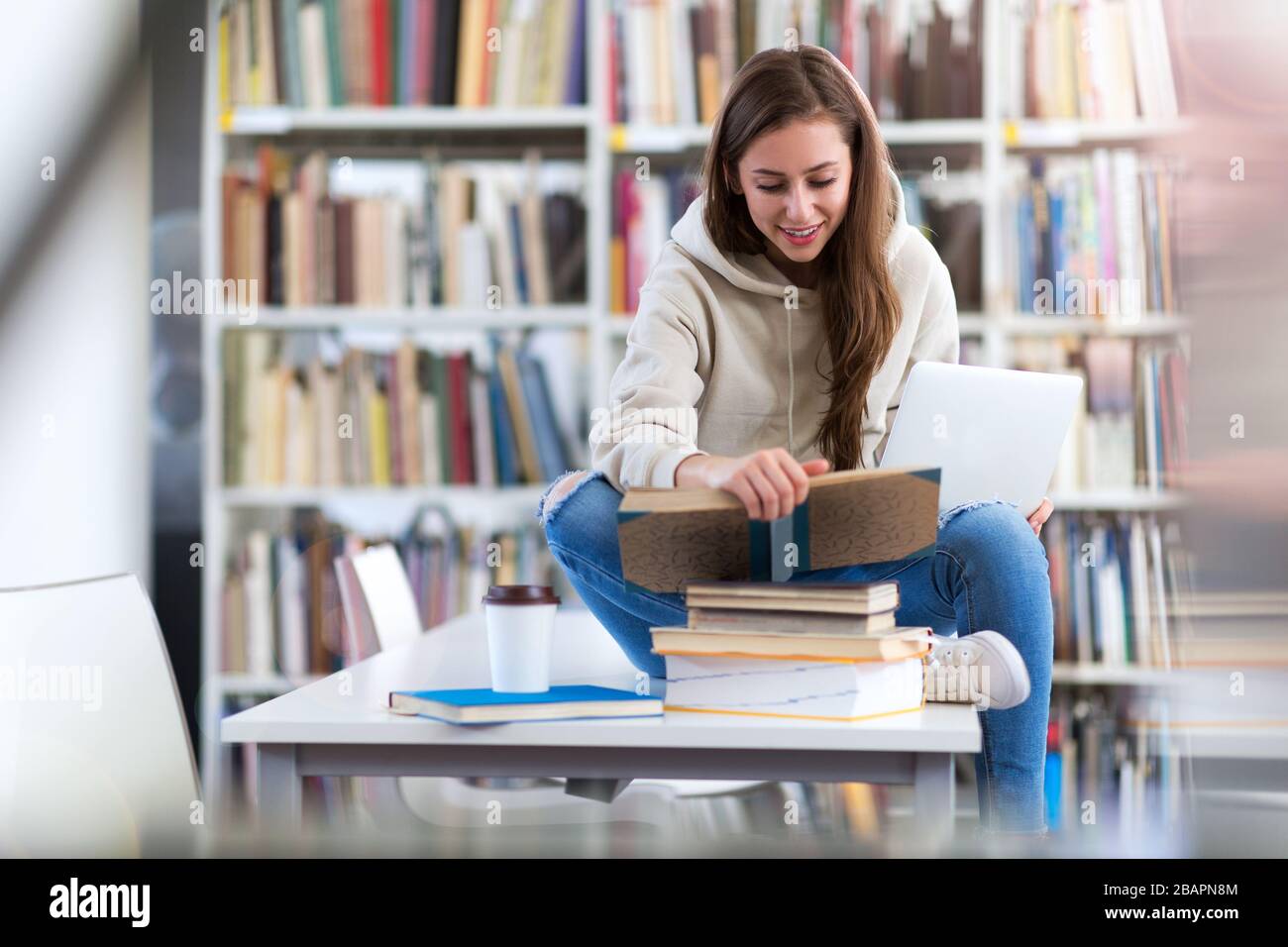 Young female student studying in the library Stock Photo - Alamy