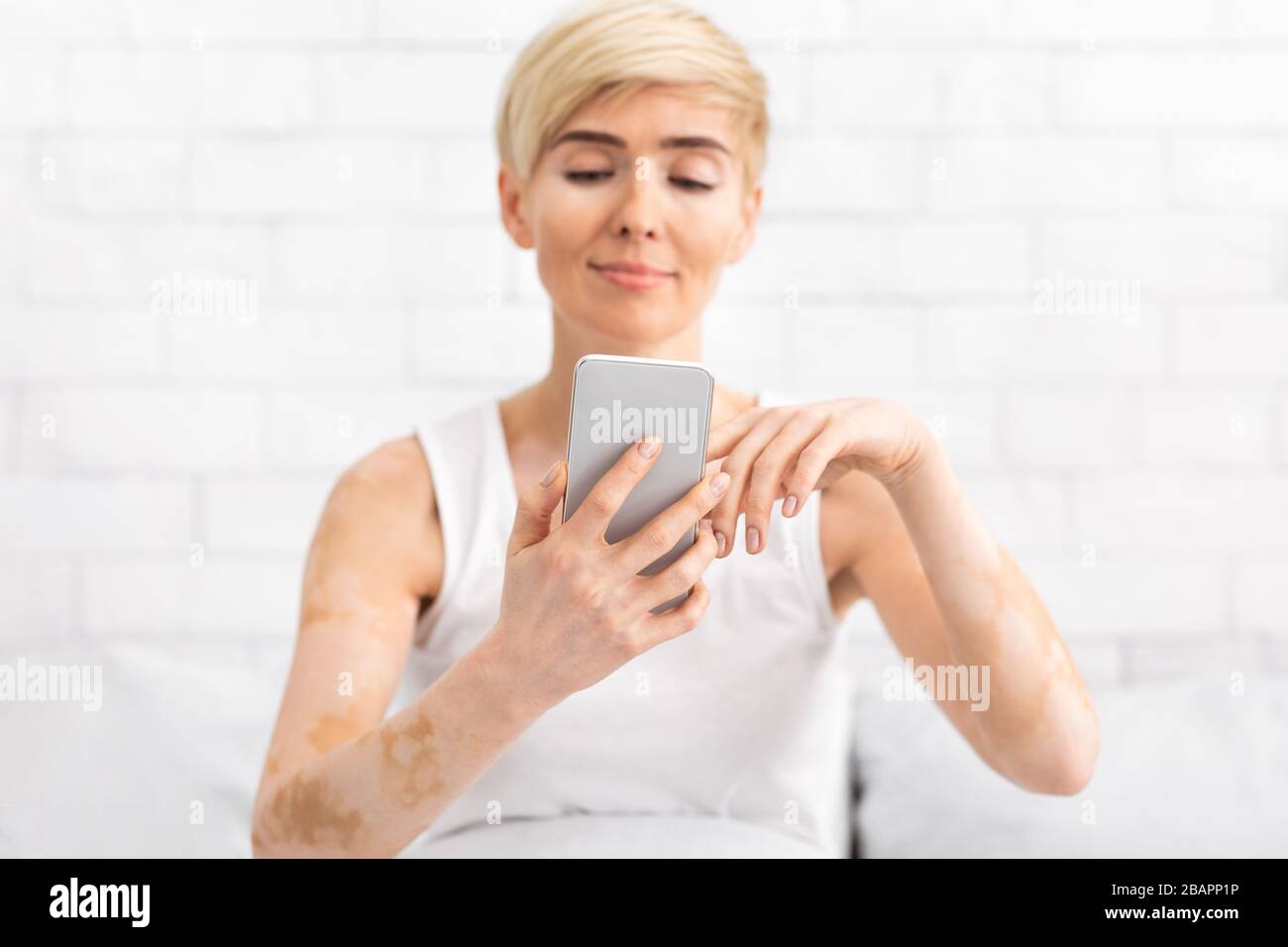 Cheerful woman texting on bed hi-res stock photography and images - Alamy