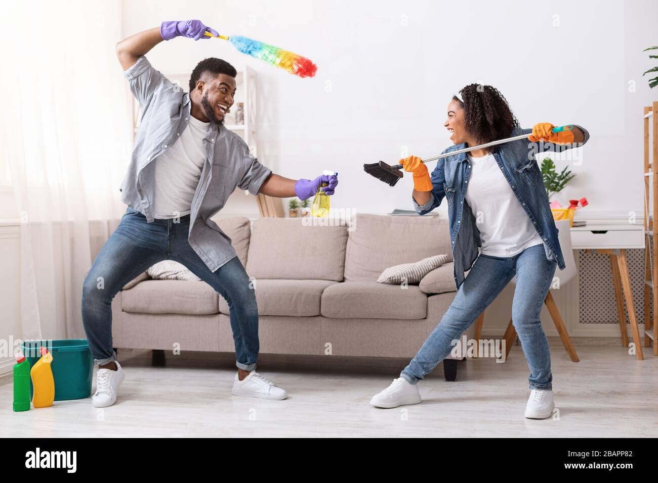 Cheerful Black Couple Fooling While Tidying Up Their Flat, Playfully ... Cheerful Black Couple Fooling While Tidying Up Their Flat, Playfully ...
