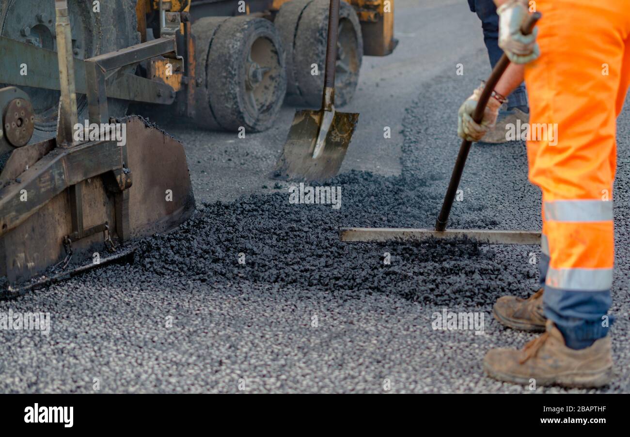 Worker regulate tracked paver laying asphalt heated to temperatures ...