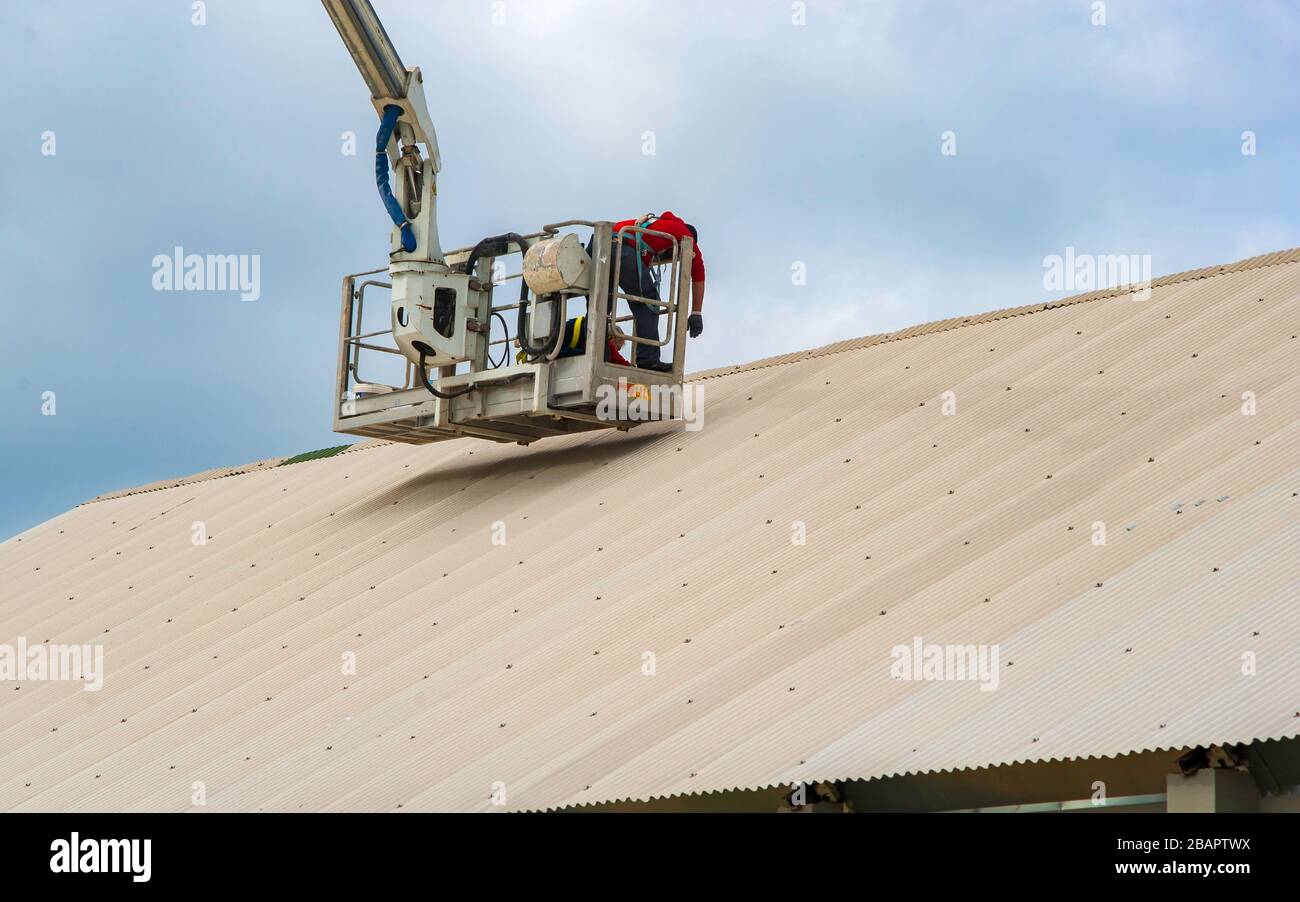 Workers in hydraulic lifting ramp repair the roof gutter. Builders on ...