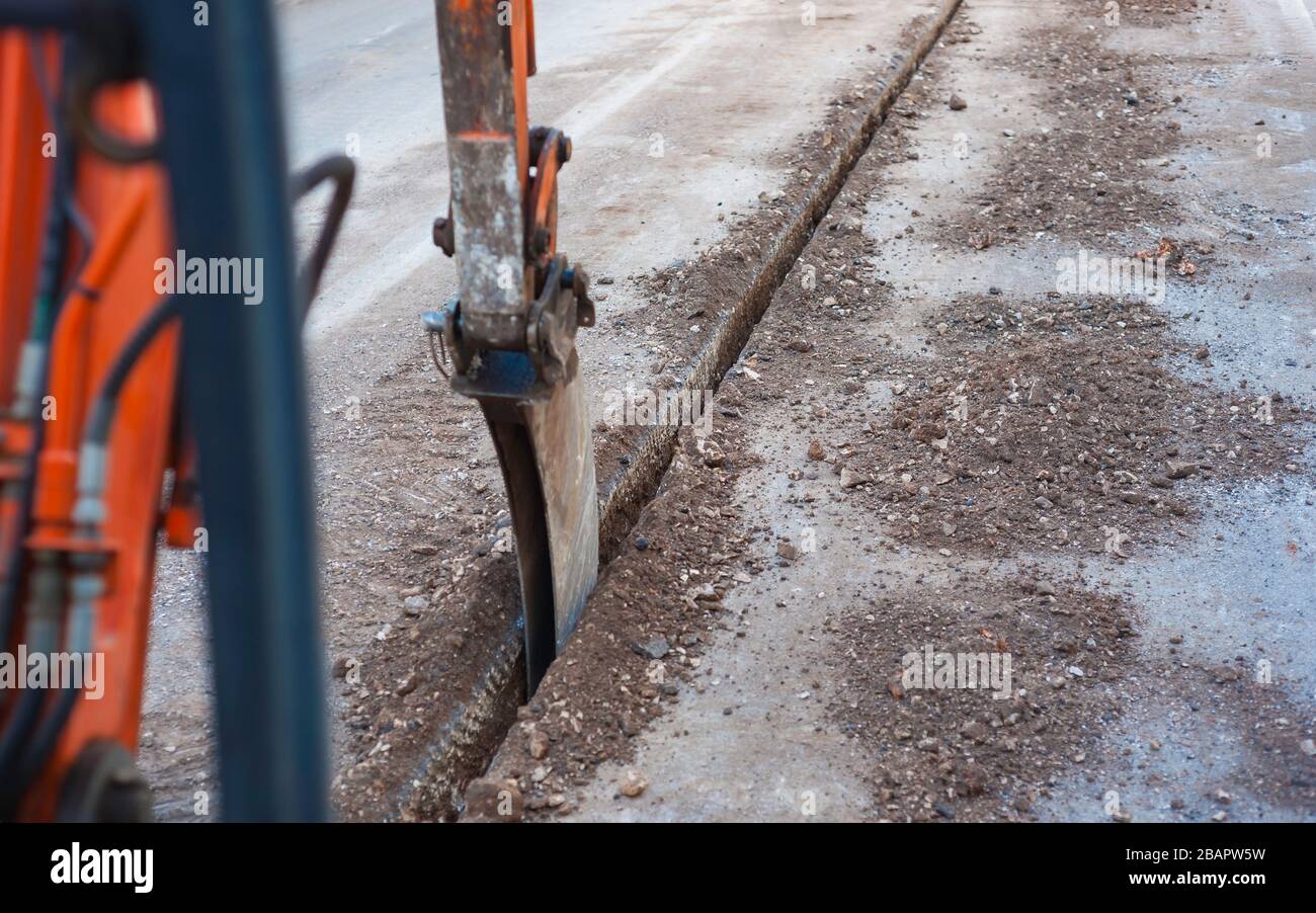 Mini excavator with narrow bucket for laying fiber-optic cable line ...