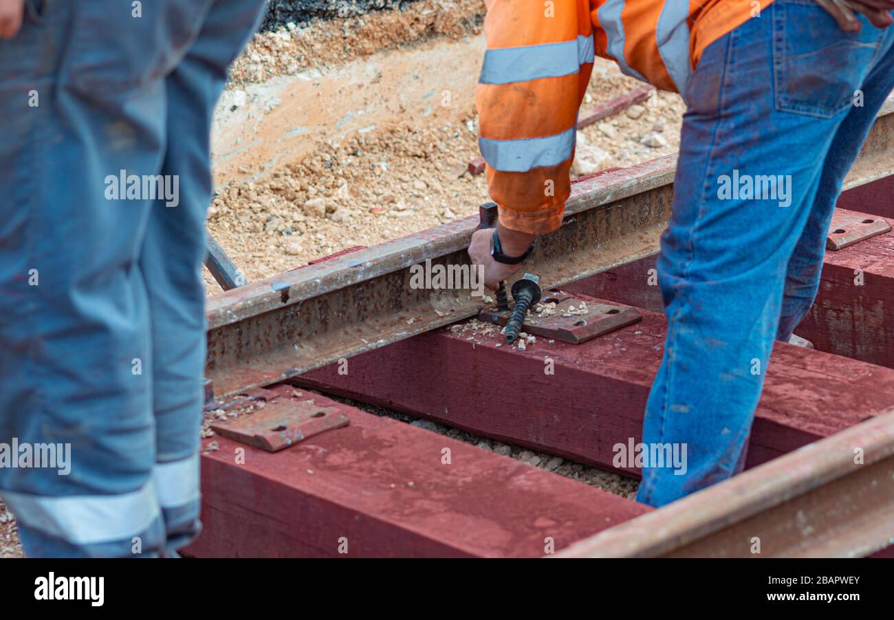 Railway workers bolting track rail. Detail worker with mechanical ...