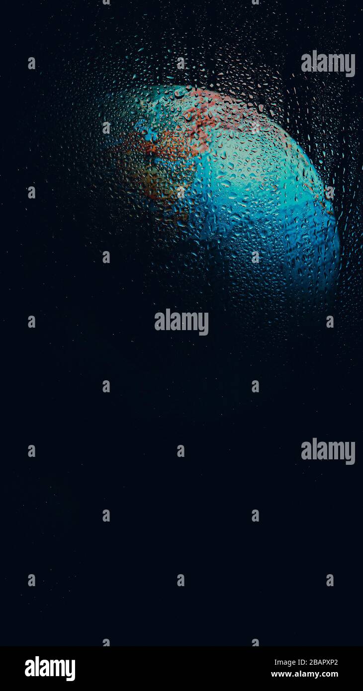 Vertical photo of planet Earth through wet glass with drops. The ...