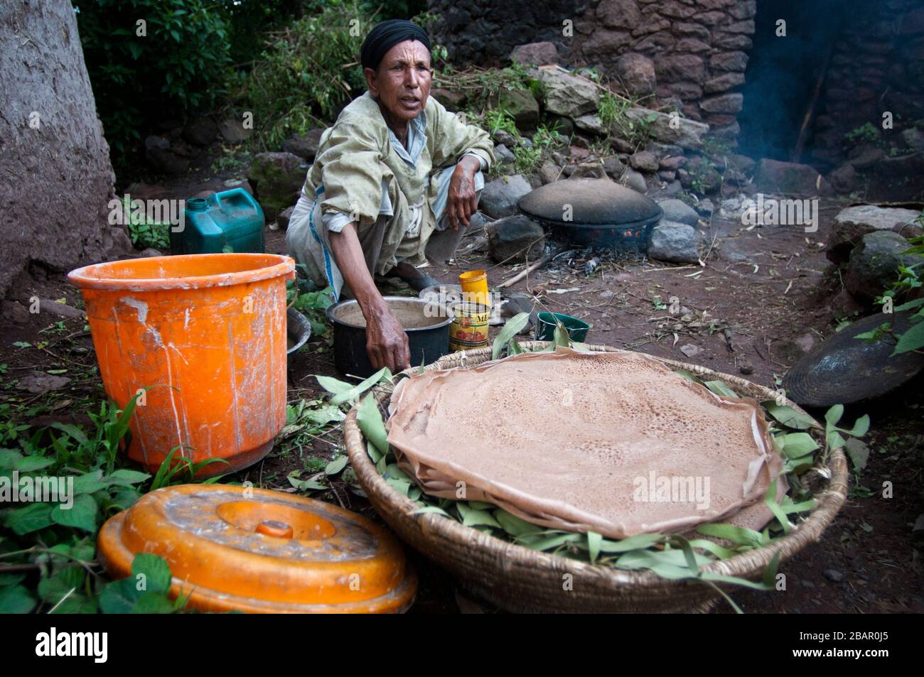 Woman cooking Injera pancake like bread on a mogogo over a fire ...