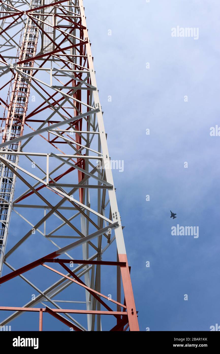 This photo shows a tall cell tower reaching up into a bright blue sky ...
