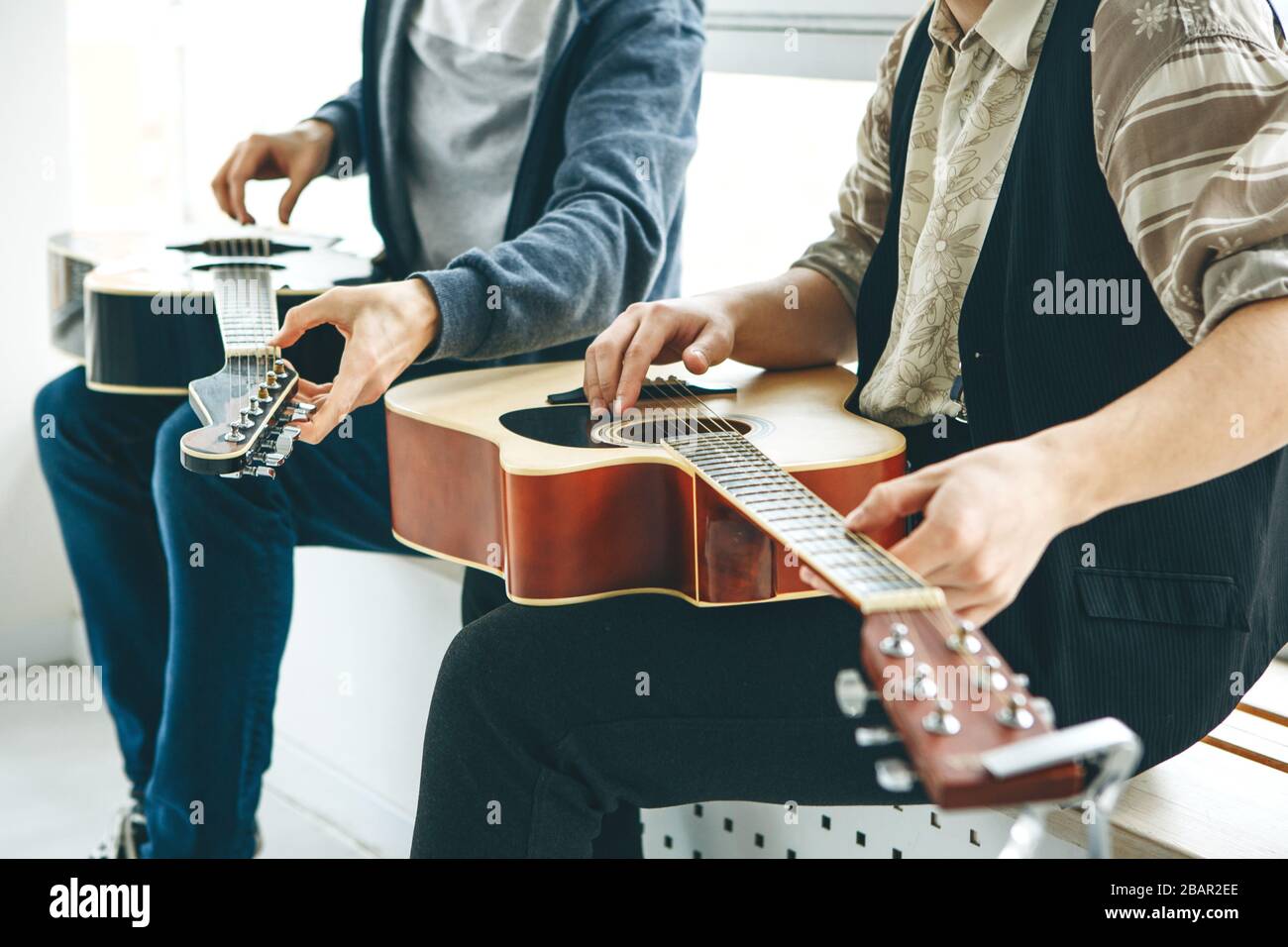 Learning to play the guitar. The teacher helps the student tune the ...