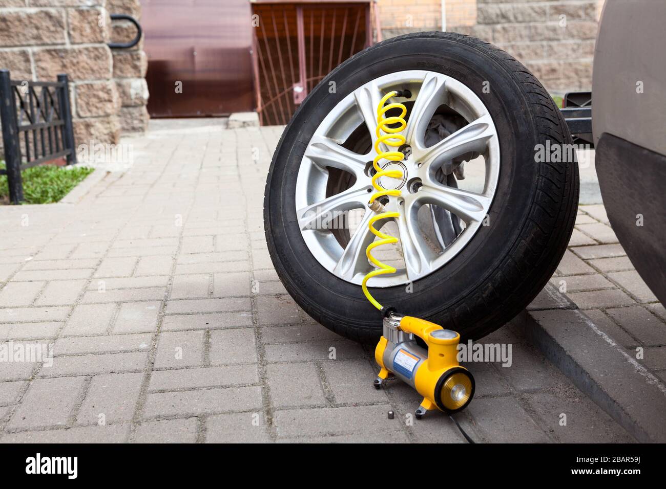Dismounted car wheel ready for inflate tyre with pneumatic pump ...