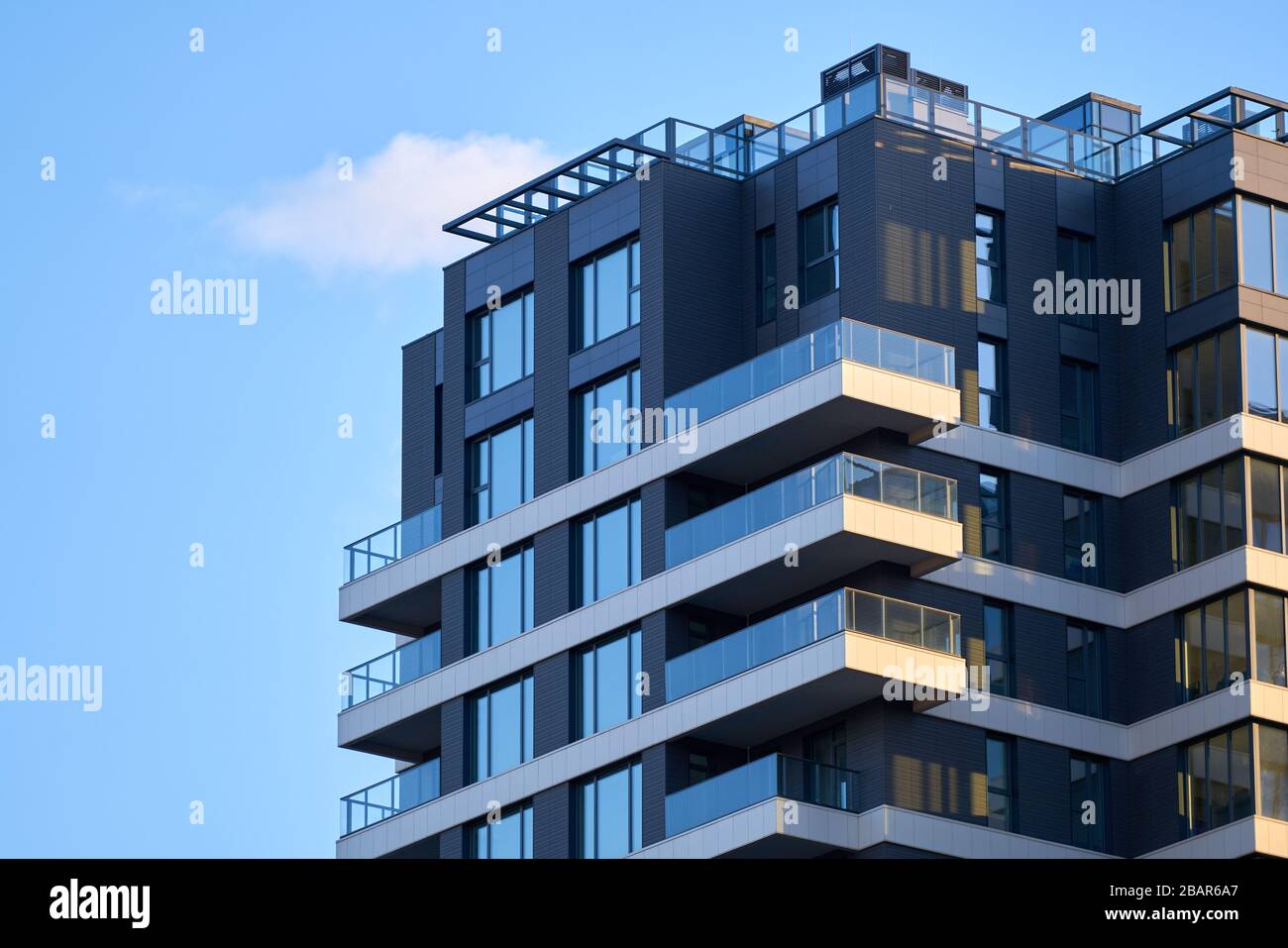 The facade of the skyscraper with balconies against the blue sky with ...