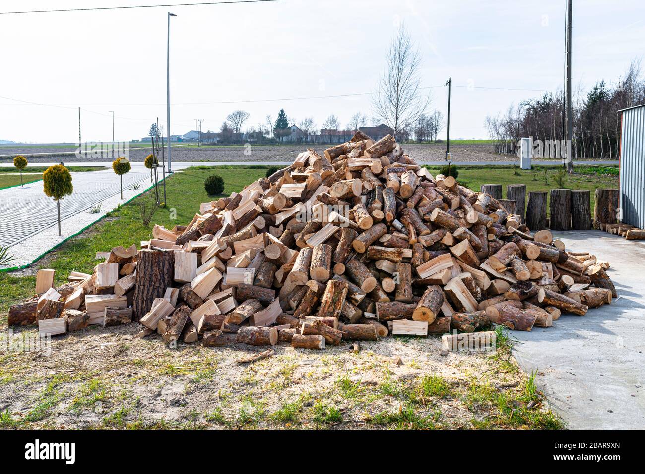 A firewood stacked in a pile, lying on the property near the metal ...