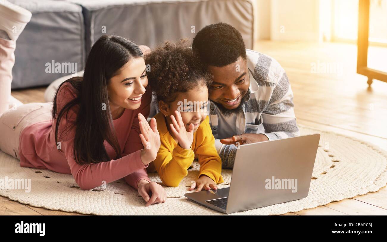 Mom and daughter waving their hands in laptop, dad smiling Stock Photo ...