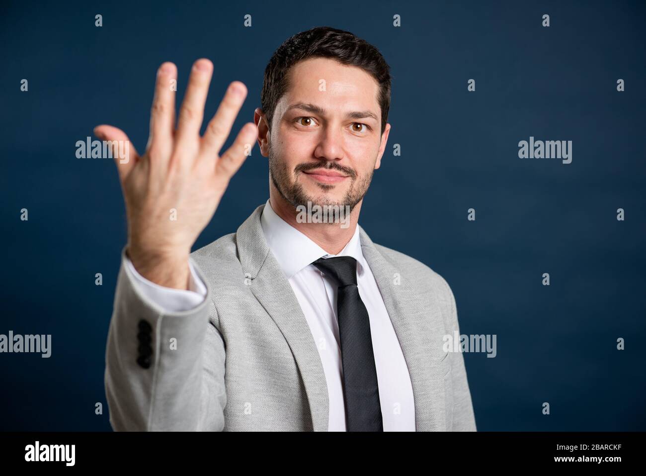 Portrait of business young handsome male showing number five gesture on ...