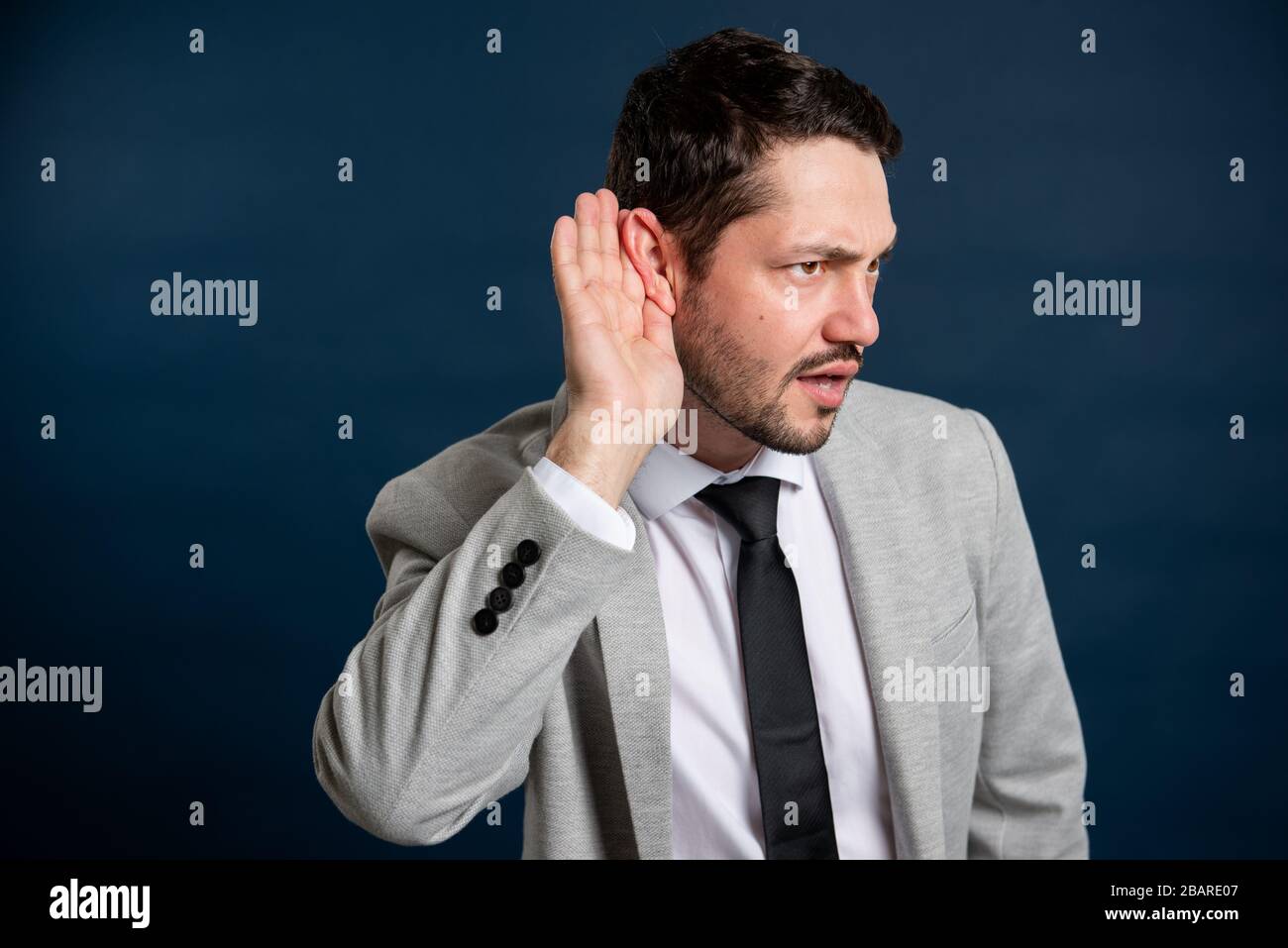 Business young handsome male making can't hear you gesture on blue ...