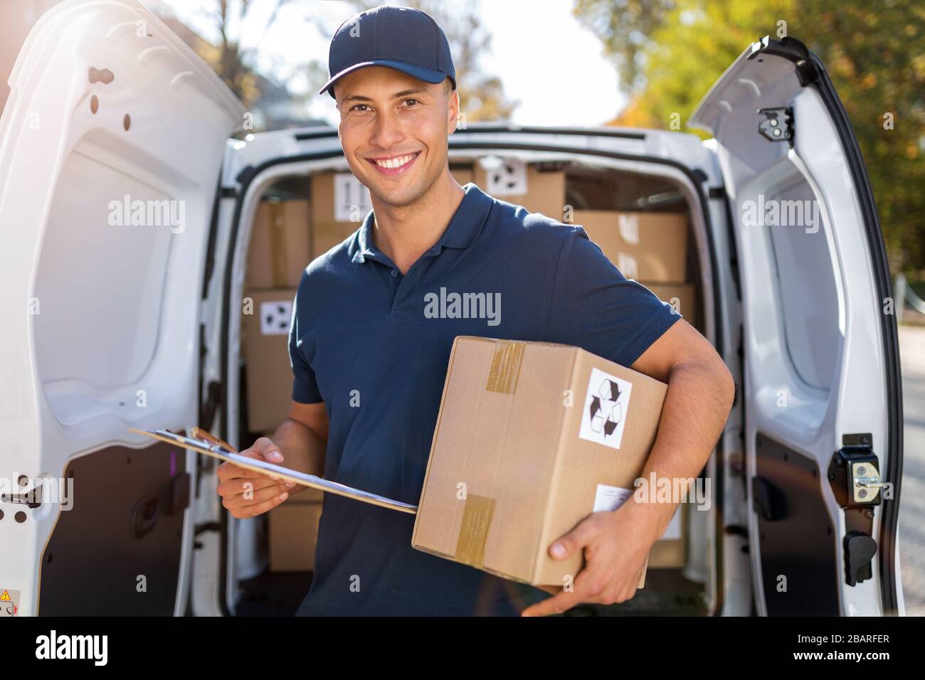 Smiling delivery man with his van Stock Photo - Alamy
