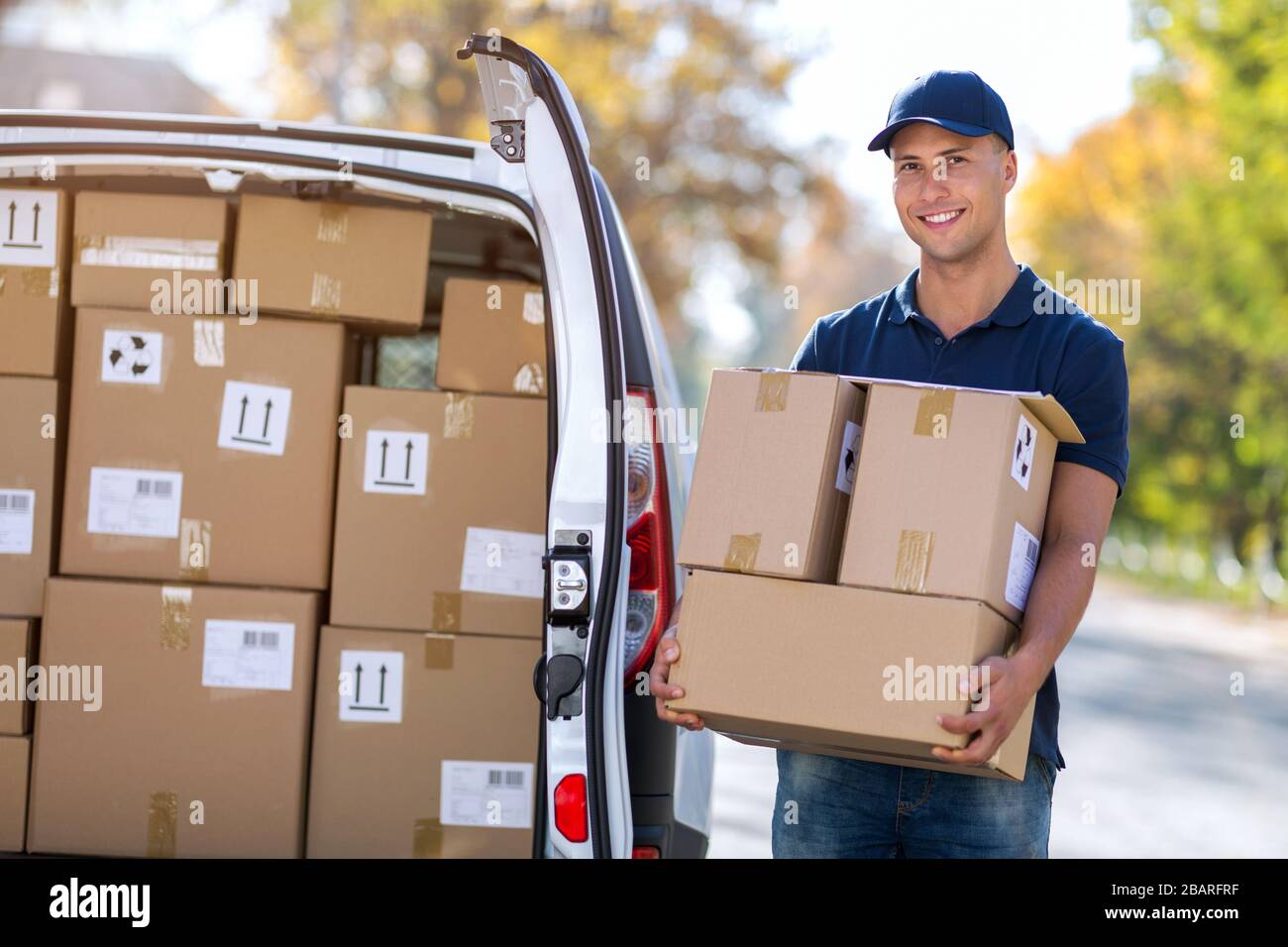 Smiling delivery man with his van Stock Photo - Alamy