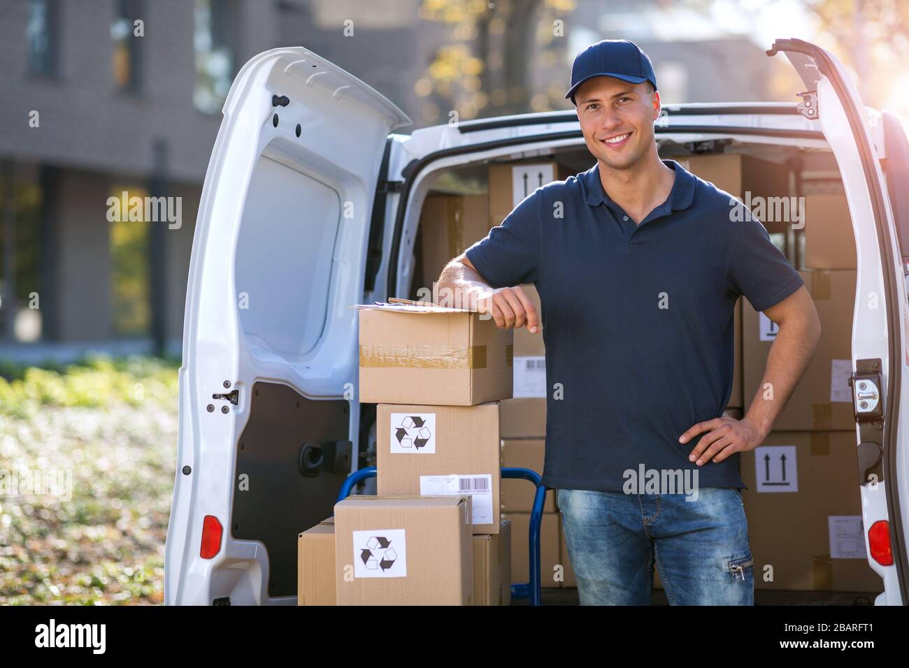 Smiling delivery man with his van Stock Photo - Alamy