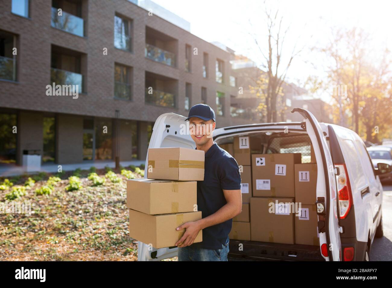 Smiling delivery man with his van Stock Photo - Alamy