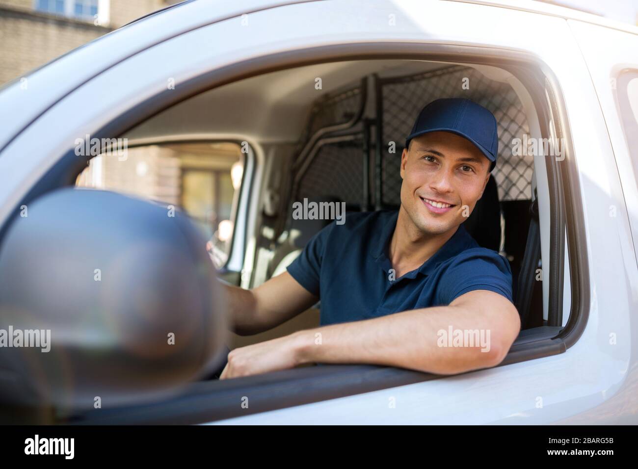 Smiling delivery man with his van Stock Photo - Alamy