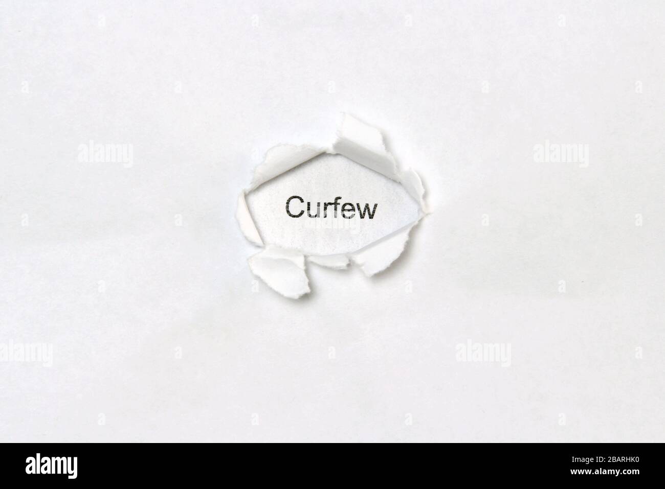 The word curfew printed in black letters on a white sheet of paper is ...