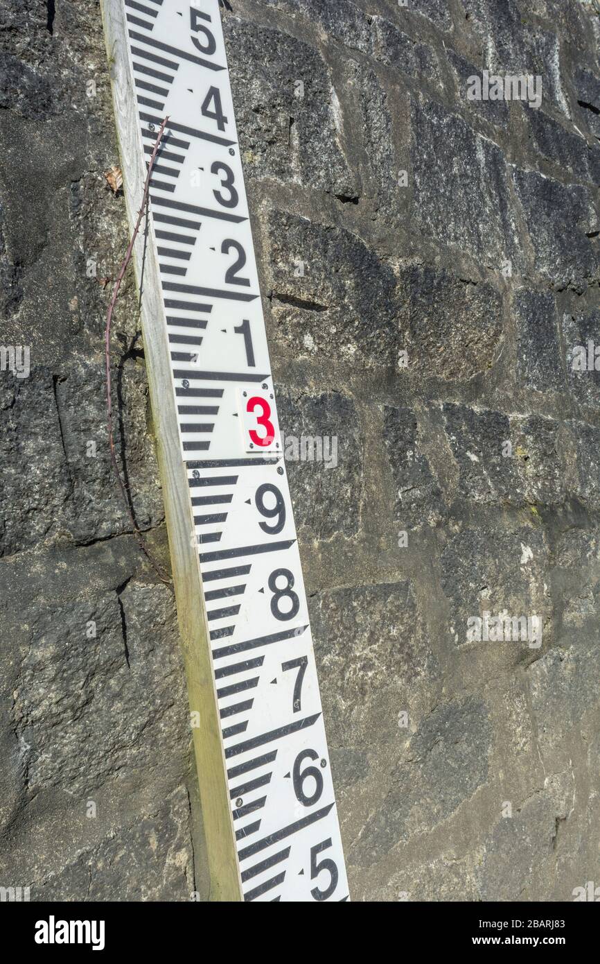 River water level measuring gauge attached to sloping barrier wall on ...