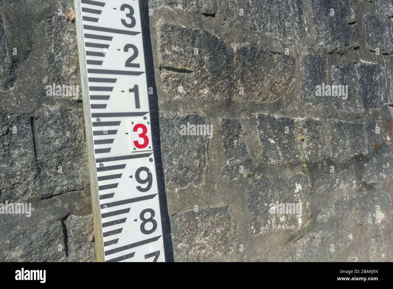 River water level measuring gauge attached to sloping barrier wall on ...