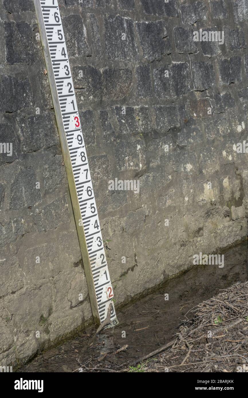 River water level measuring gauge attached to sloping barrier wall on ...