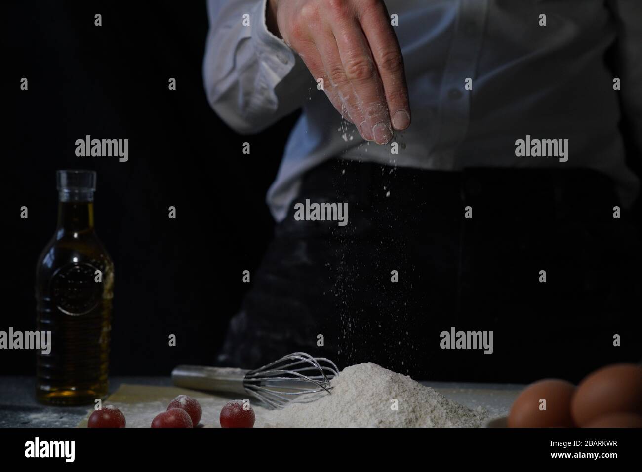 Person pouring flour from his hand onto the table to prepare food Stock ...