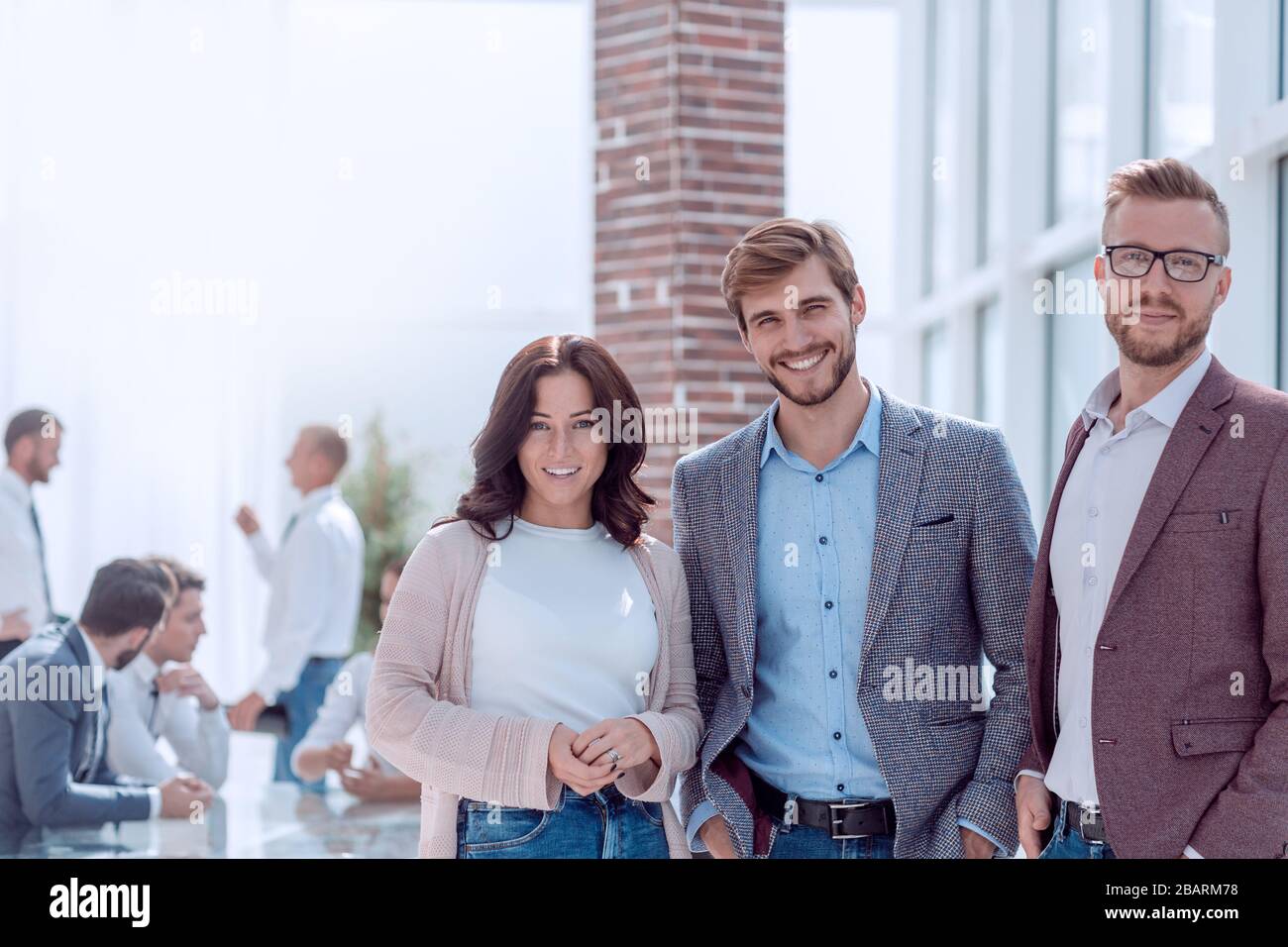 three young employees standing in a modern office Stock Photo - Alamy