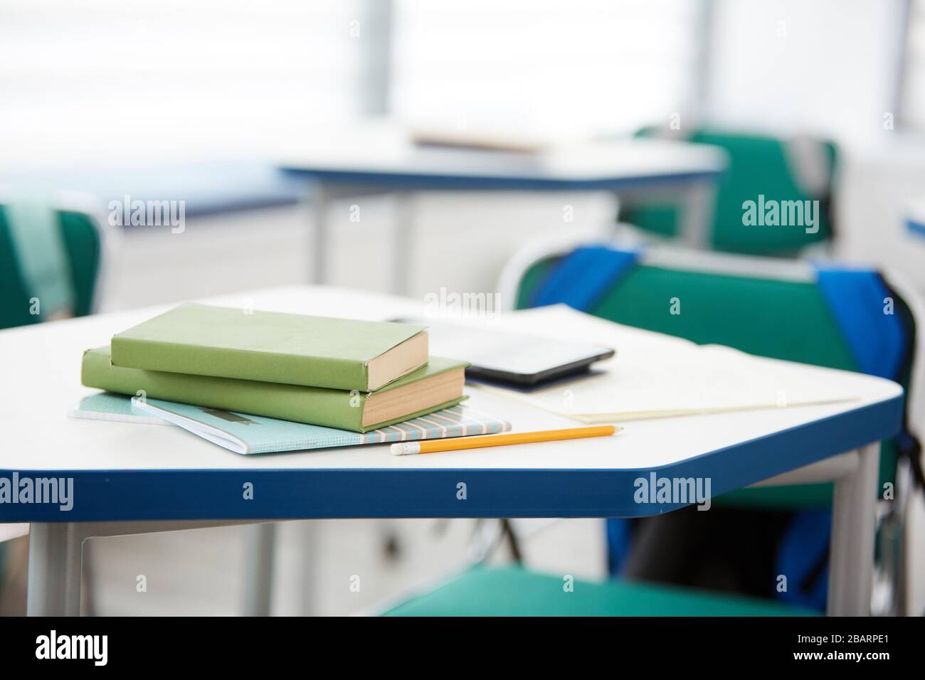 Background close up of green books stacked on desk in school classroom ...