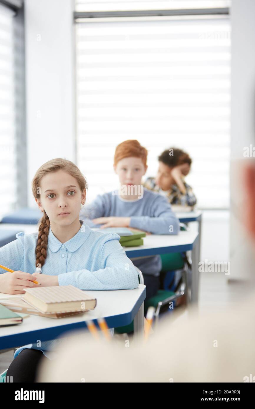 Multi-ethnic group of children sitting in row at desk in school ...