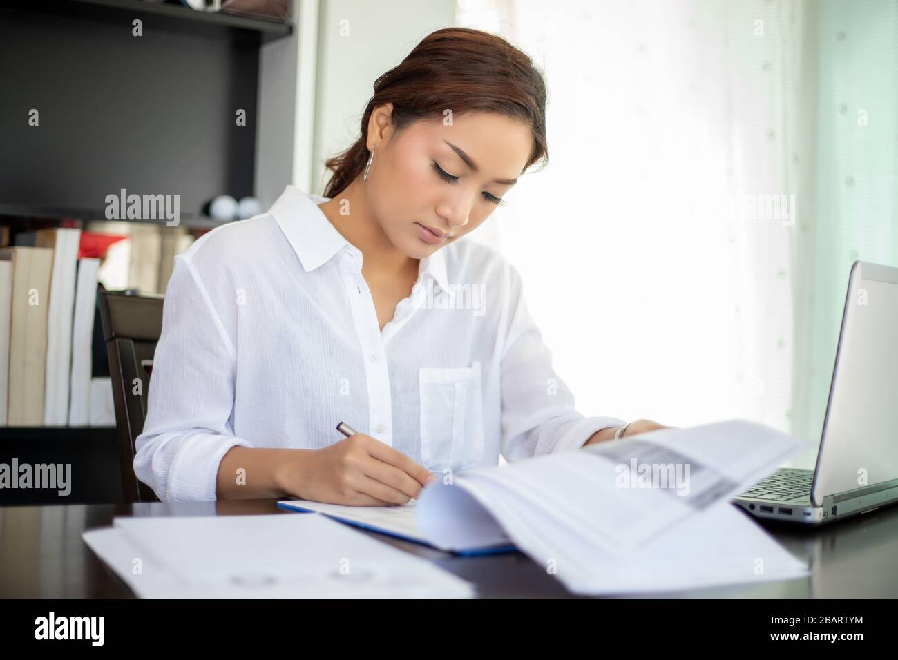 Beautiful Asian business women checking document and using notebook ...